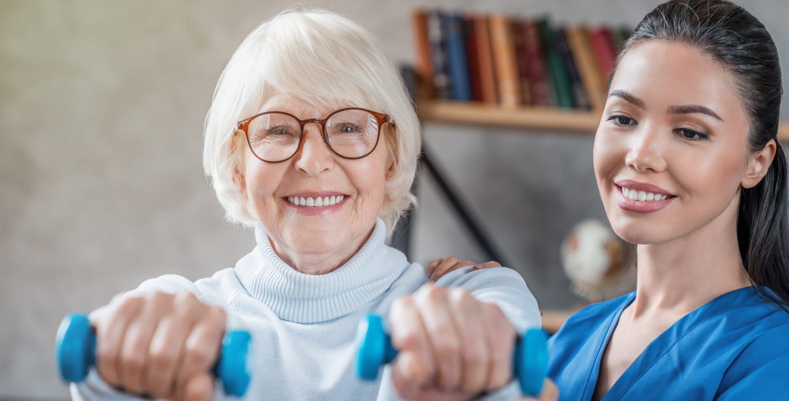Old woman training with physiotherapist using dumbbells at home - Give BSMH