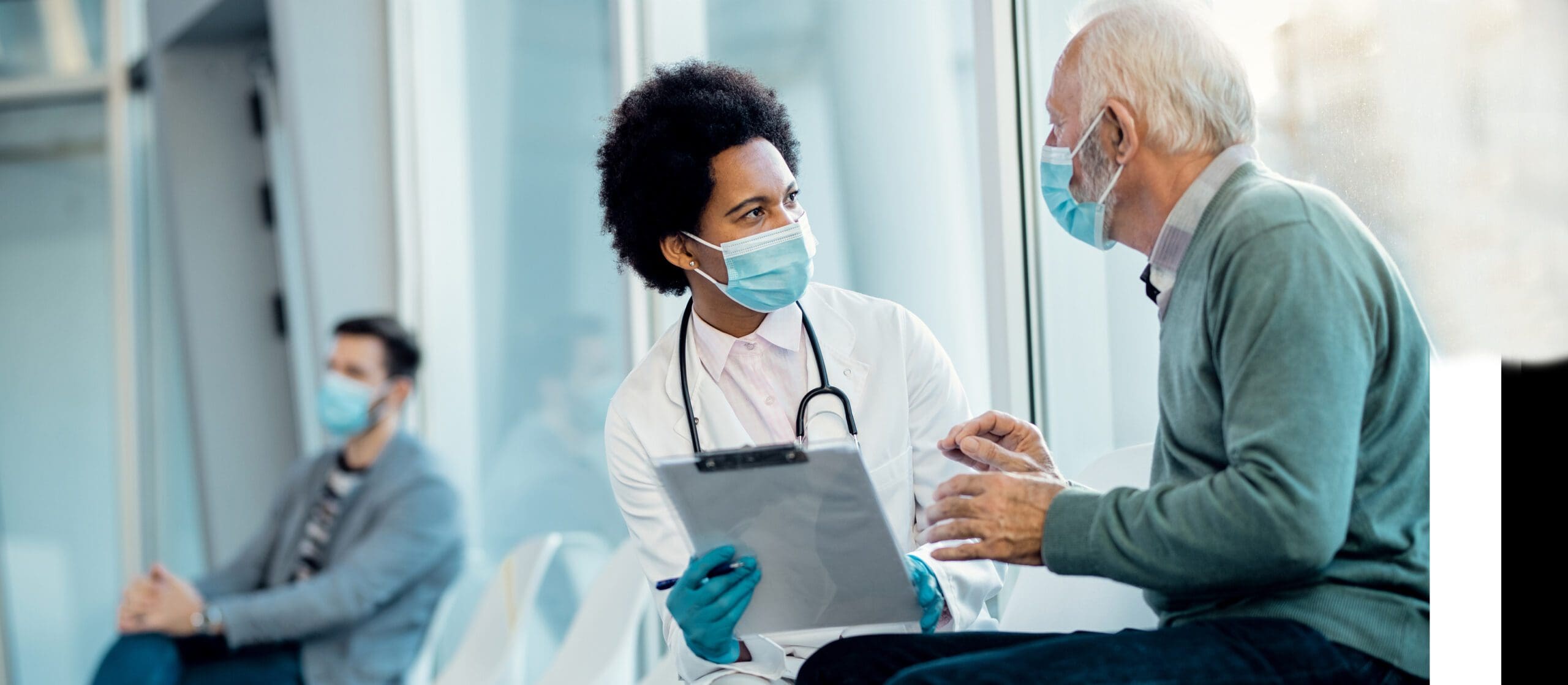 Black female doctor and senior man wearing face masks while talking ...