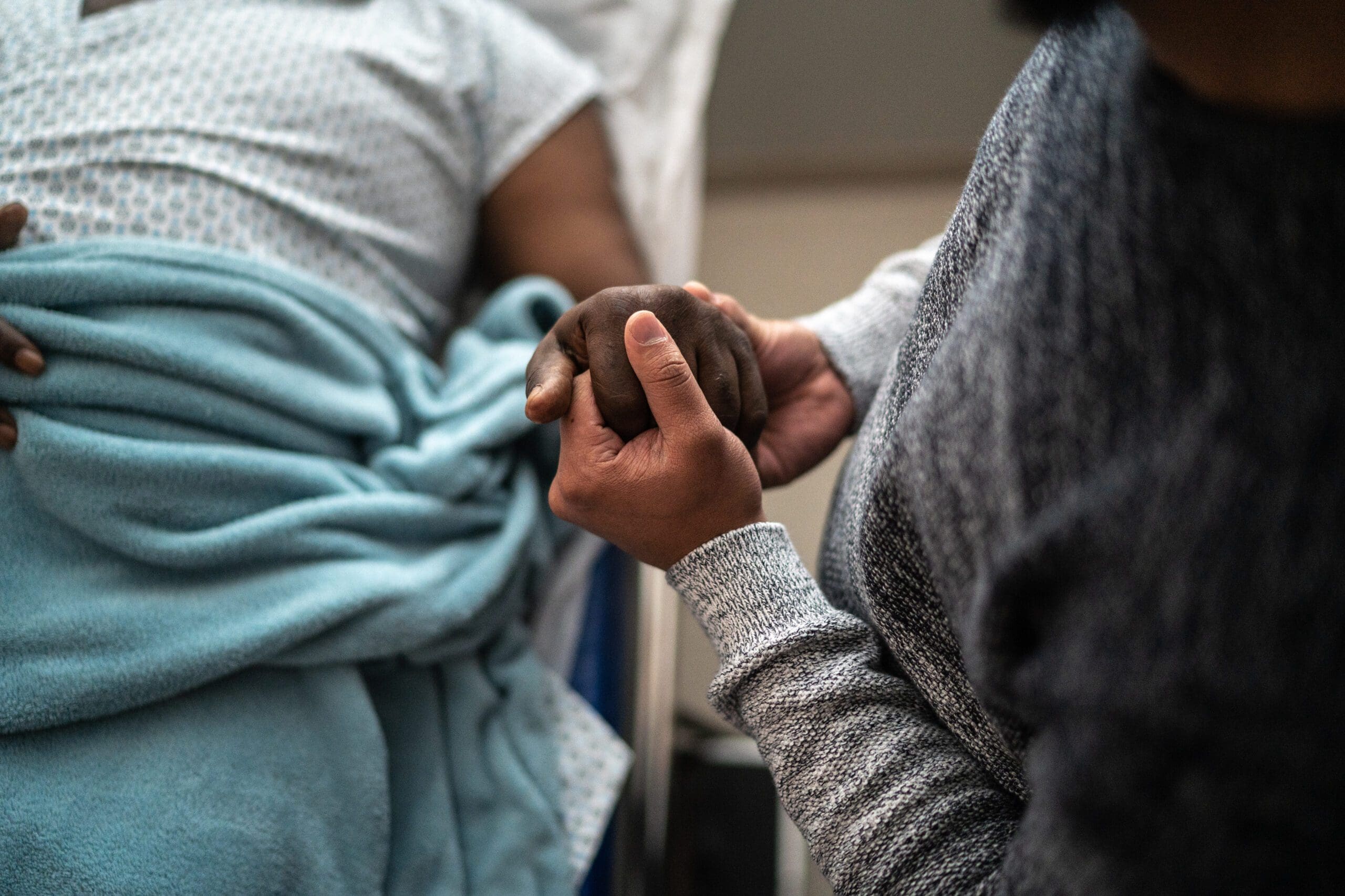 Son holding father’s hand at the hospital - Give BSMH