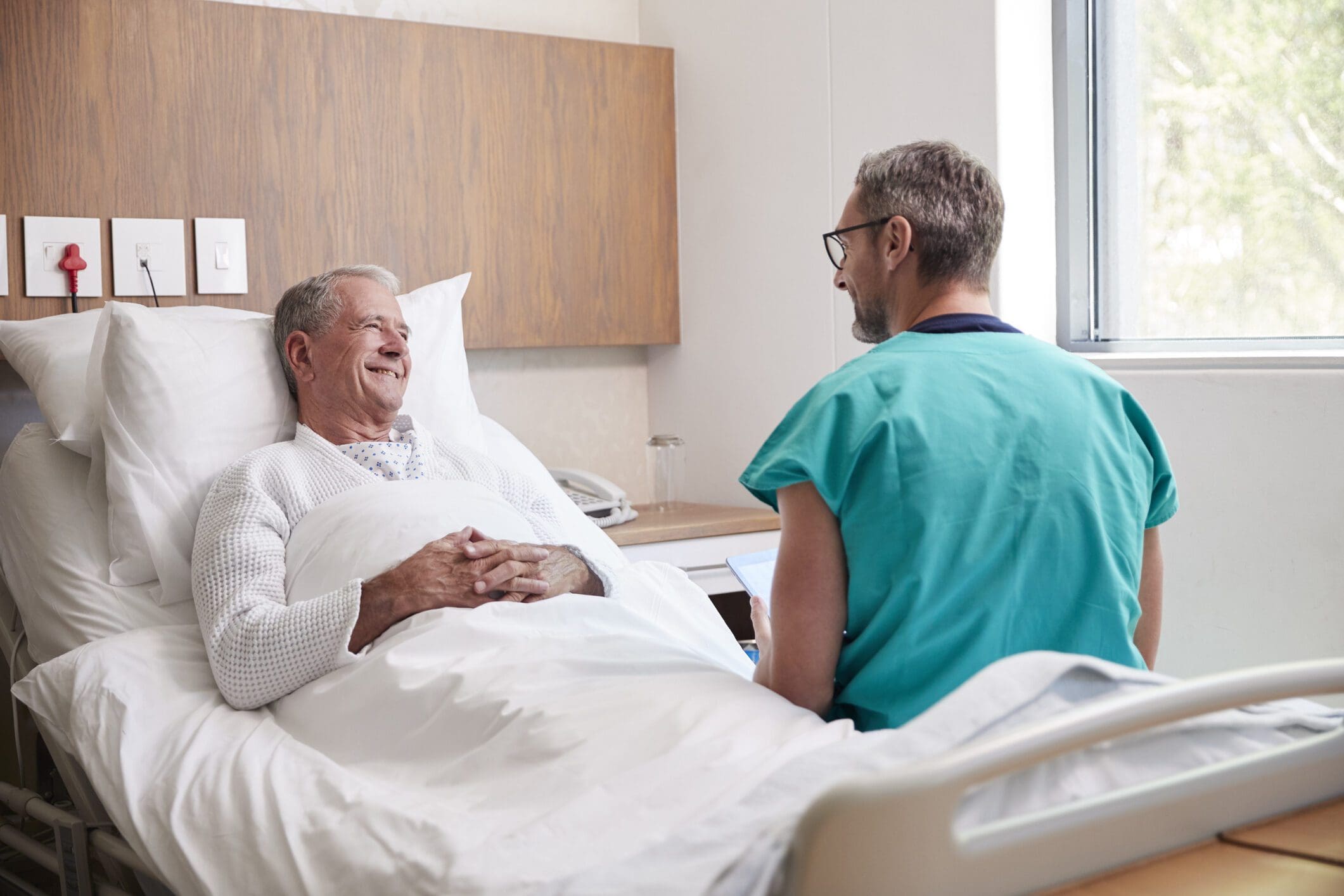 Surgeon With Digital Tablet Visiting Senior Male Patient In Hospital ...